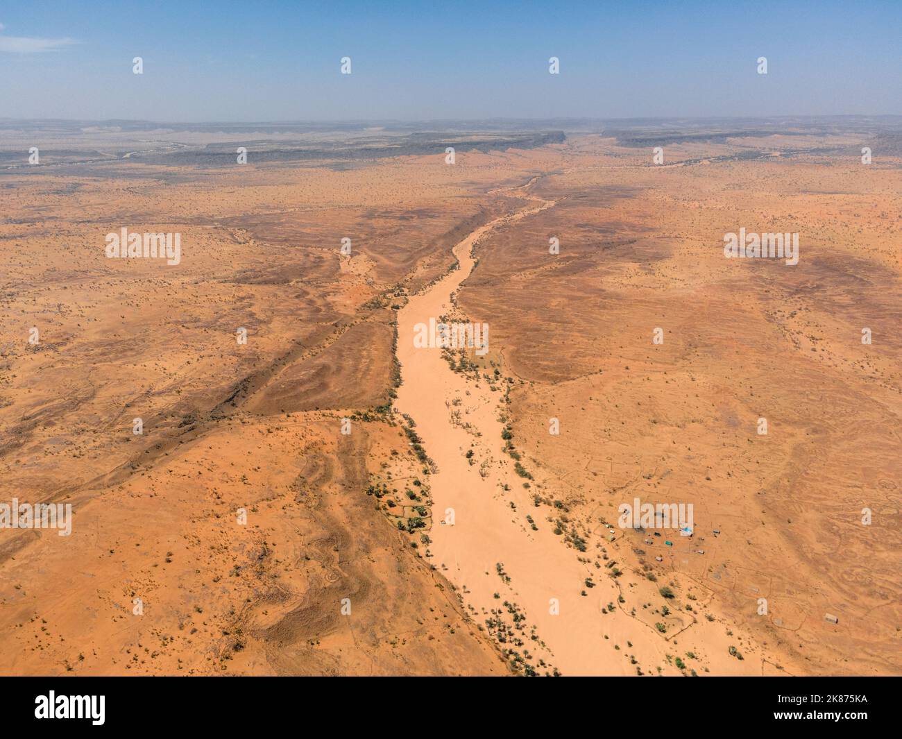 A river bed, palms, and dunes surround the village of Kamour ...