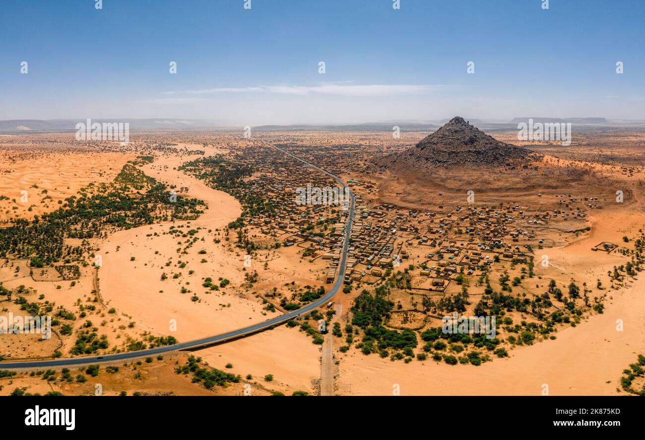 A crumbling mountain, a river bed, palms, and dunes surround the ...