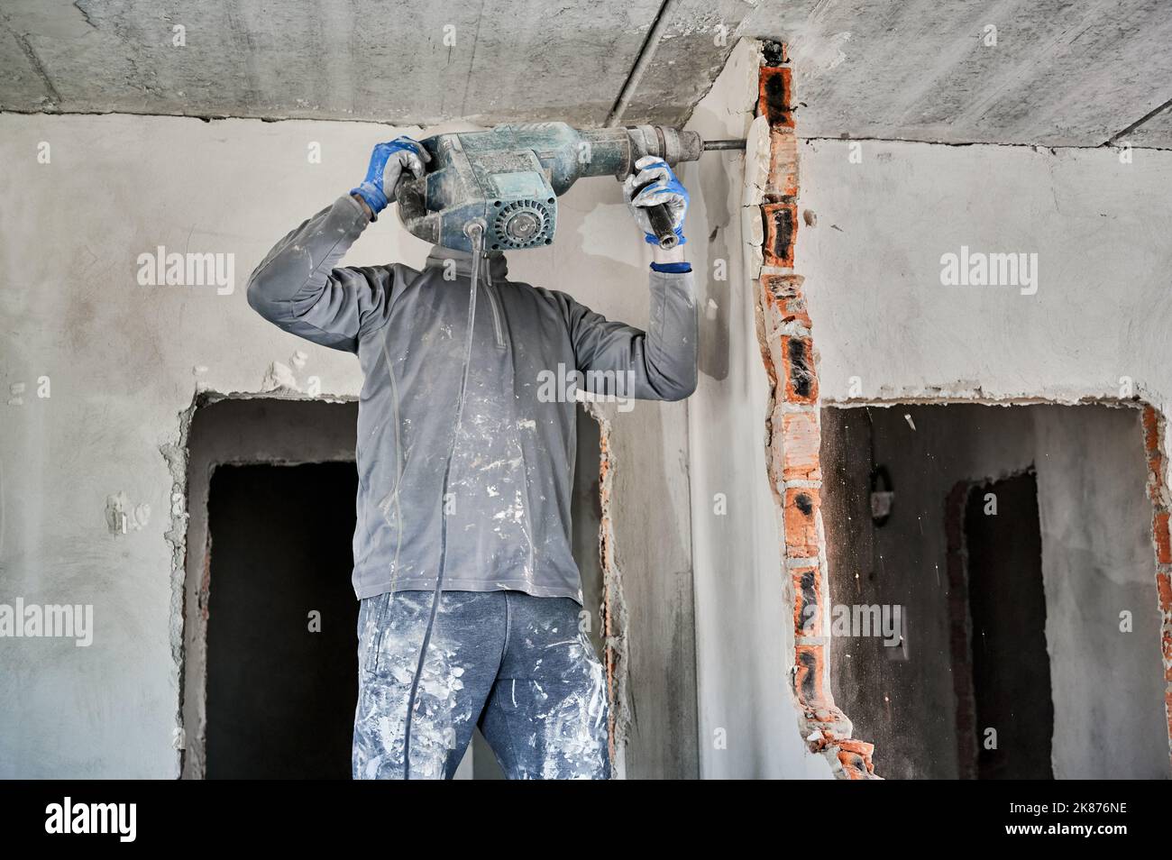Strong repairman working with heavy special tool for destroying walls. Side view of builder with ...
