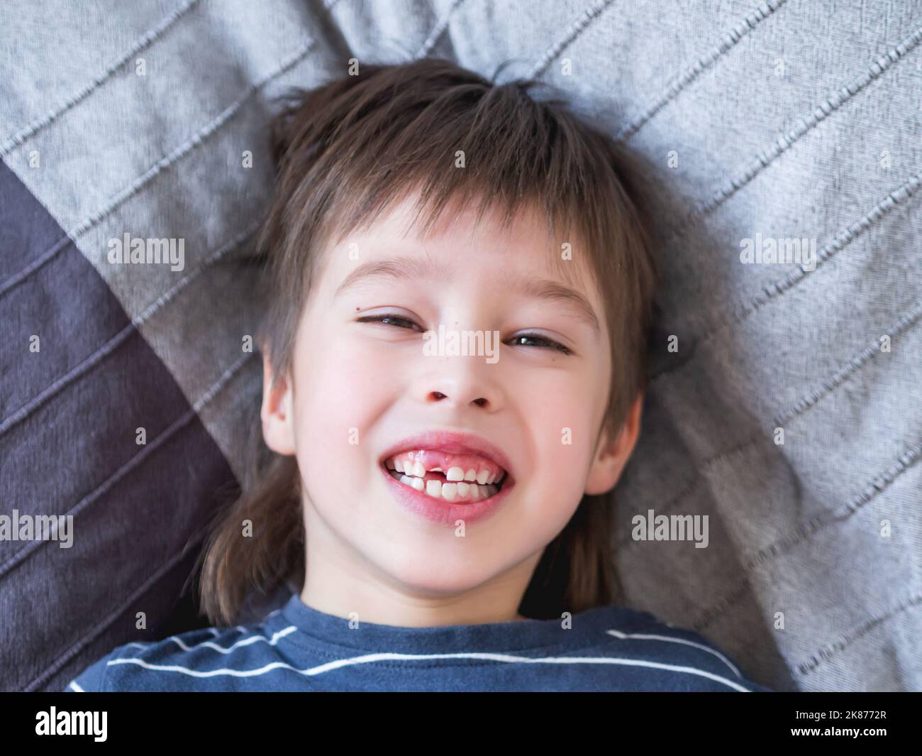 Laughing kid shows hole in row of teeth in his mouth. One incisor fell ...