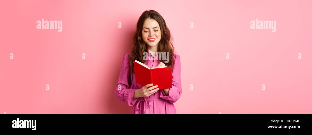 Attractive modern woman writing in her diary, making notes in notebook ...