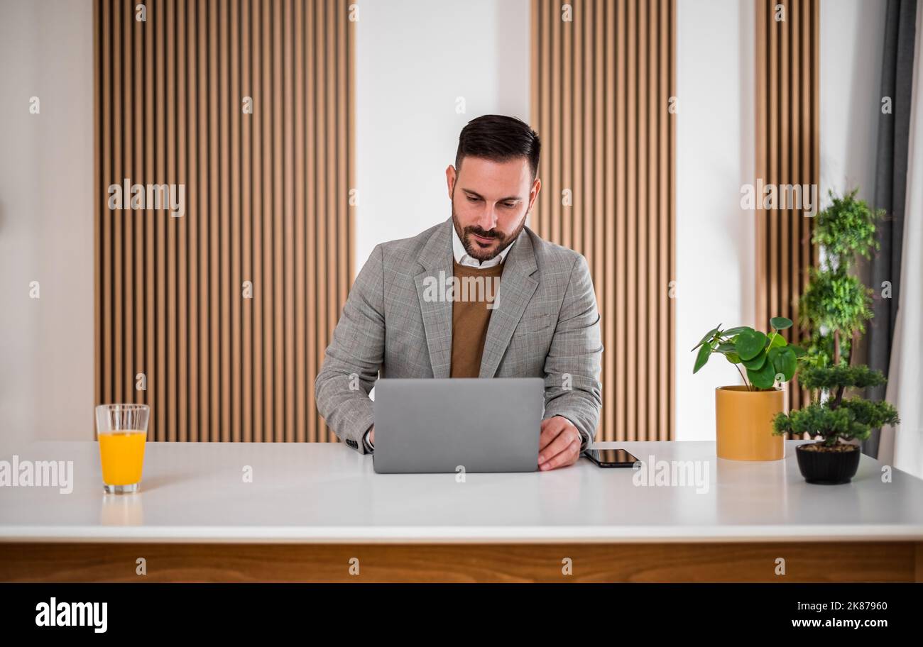 Diligent adult businessman, having a busy day at the office, using ...