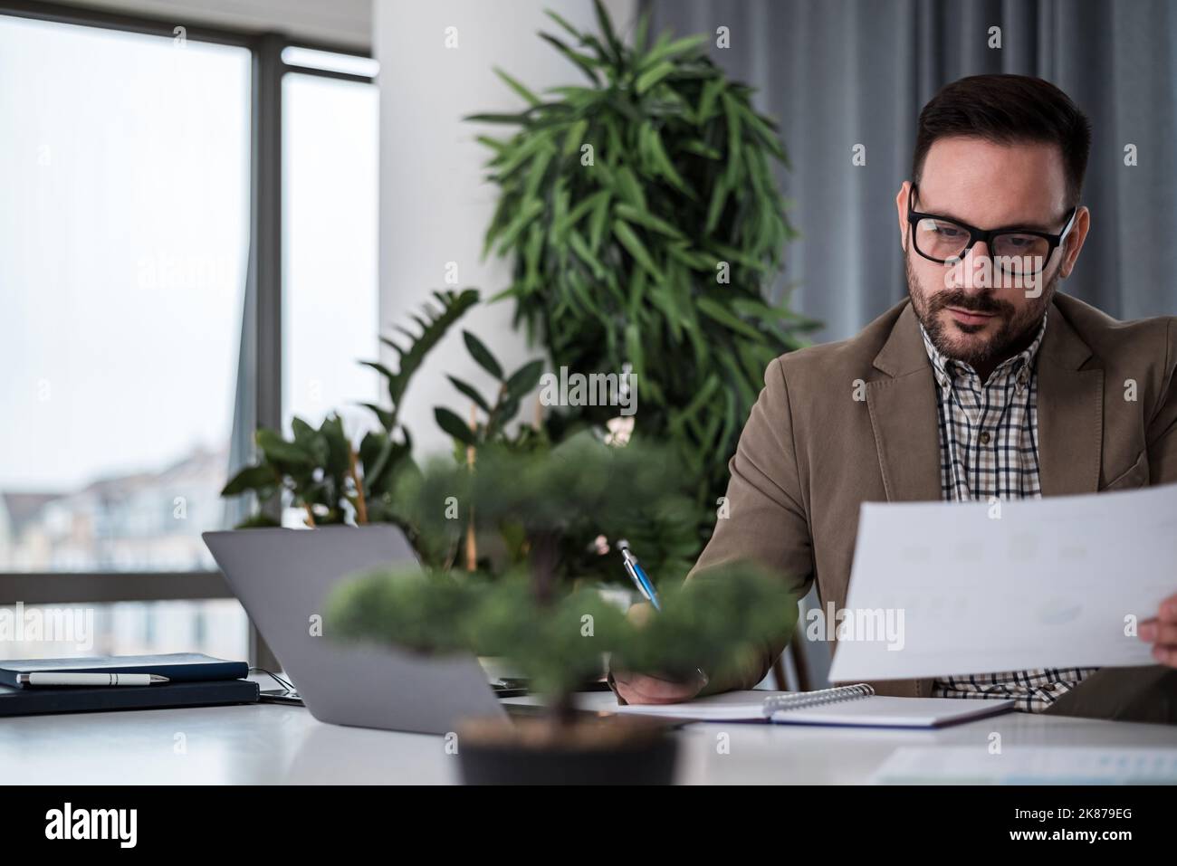 Concentrated adult man with eyeglasses, checking the company files ...