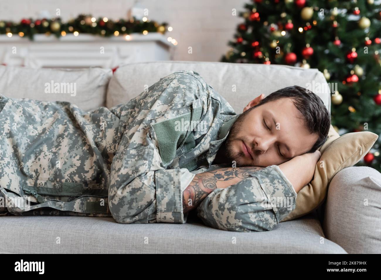 tired bearded man in military uniform sleeping on couch at home on ...