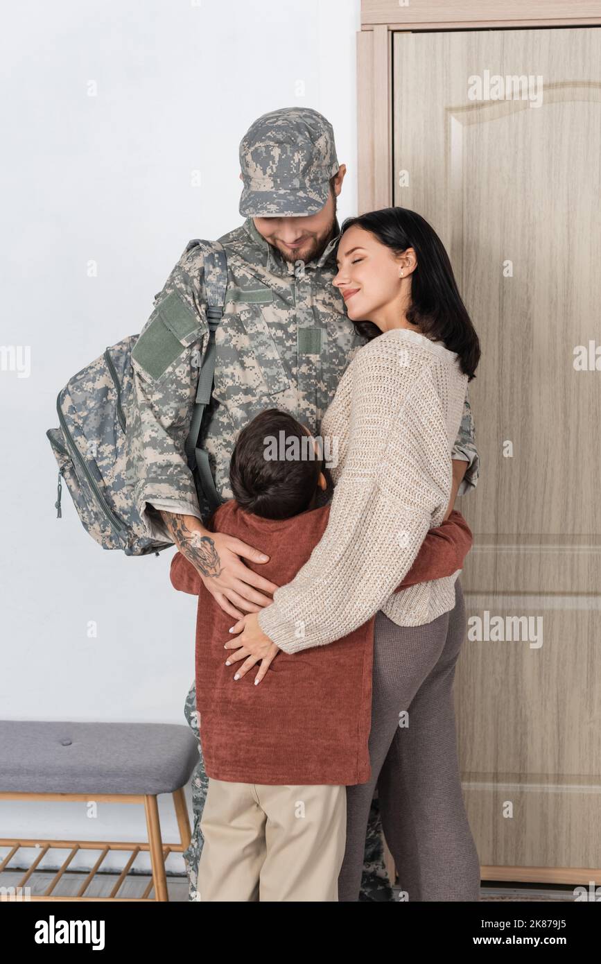 happy mother and child embracing man in military uniform coming back ...