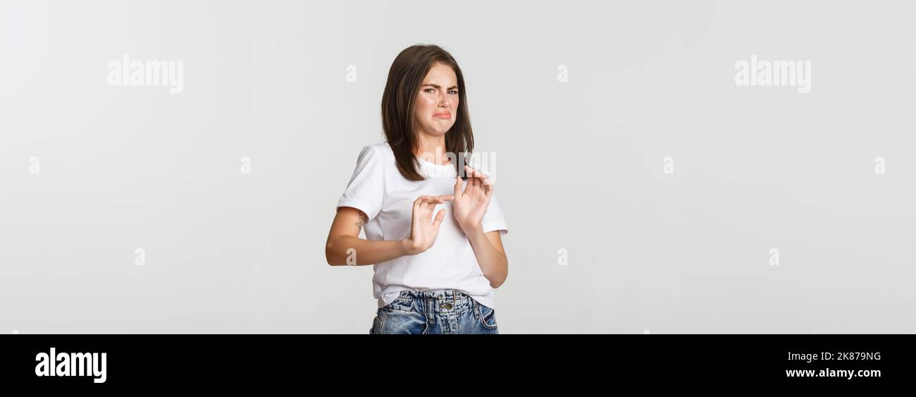 Disgusted young brunette girl grimacing and showing stop gesture ...