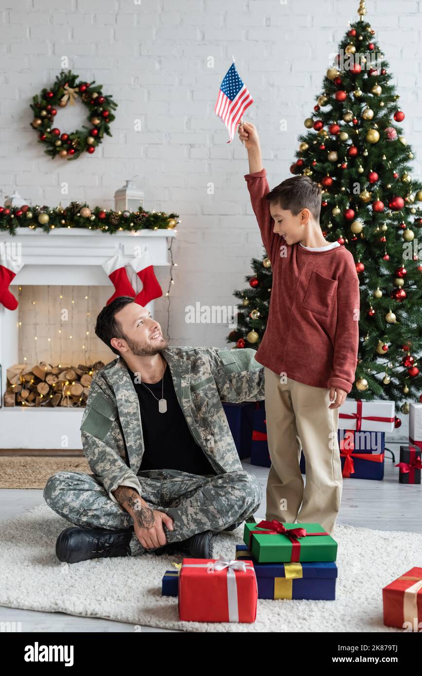 patriotic boy holding usa flag near smiling father in military uniform ...