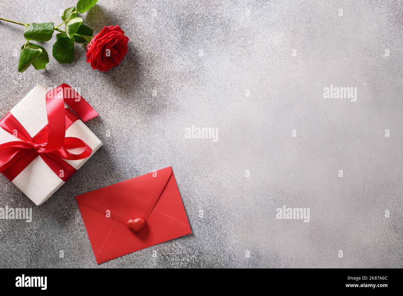 Valentine's day romantic gift, red rose and red envelope on gray ...
