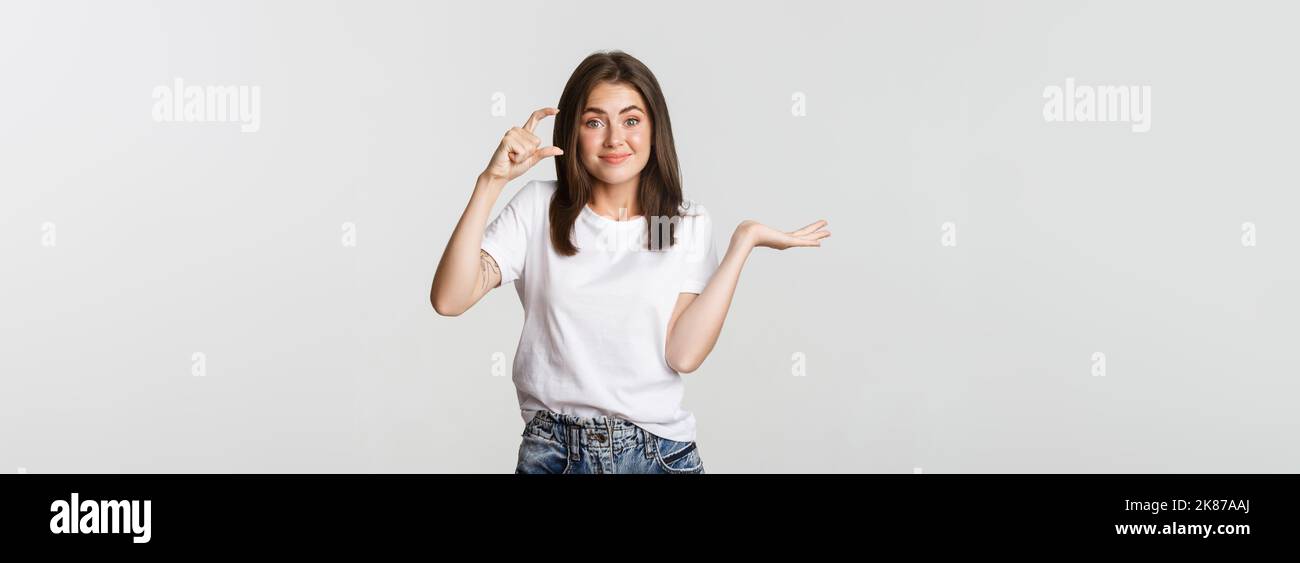 Skeptical and unamused brunette girl showing something too small, tiny ...