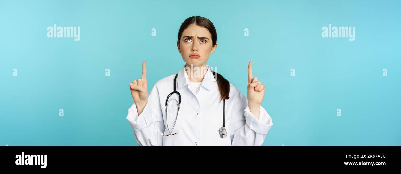 Sad and gloomy doctor, female medical worker sulking, pointing and ...