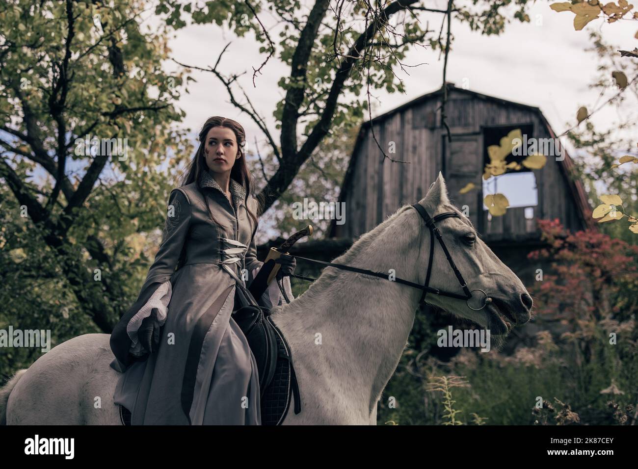 Young woman in image of ancient rider warrior sits on white horse with ...