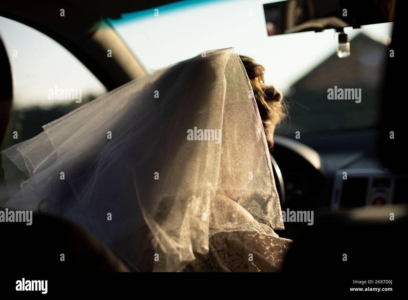 Bride is driving car. Woman in white veil in transport. Girl in car ...