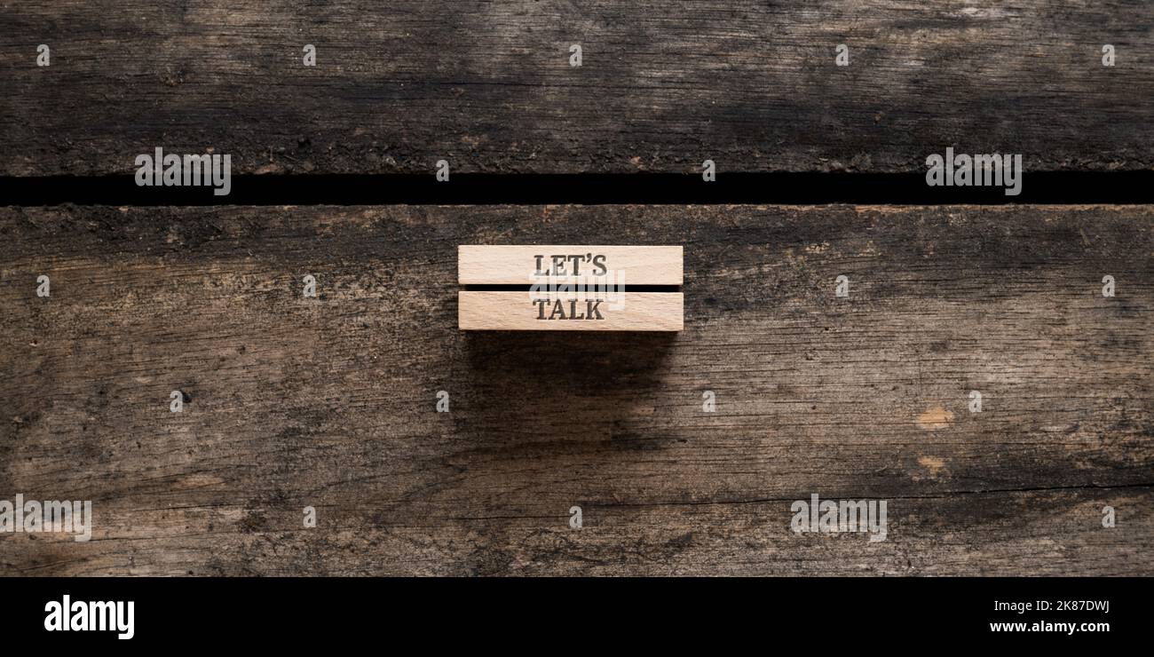 Lets talk sign written on two wooden pegs placed on rustic wooden ...