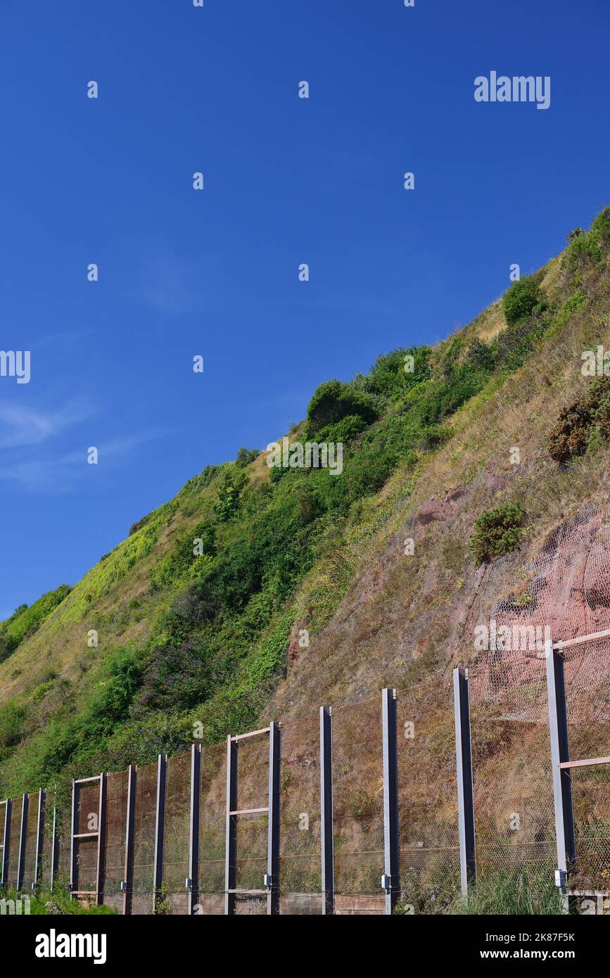 A deep blue sky above red sandstone cliffs, and fencing protecting the ...