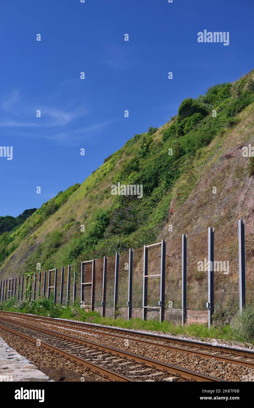 A deep blue sky above red sandstone cliffs, and fencing protecting the ...