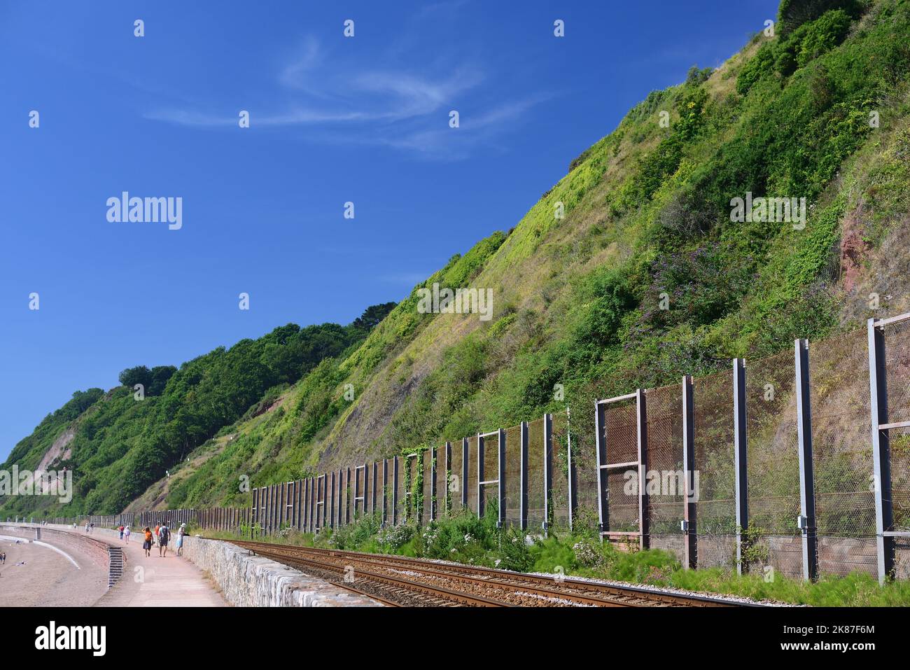 A deep blue sky above red sandstone cliffs, and fencing protecting the ...