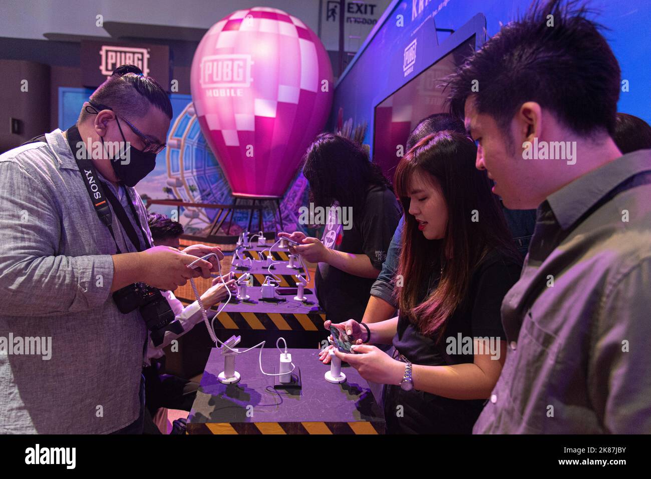 Visitors seen playing a game on mobile phones during the Thailand Game ...