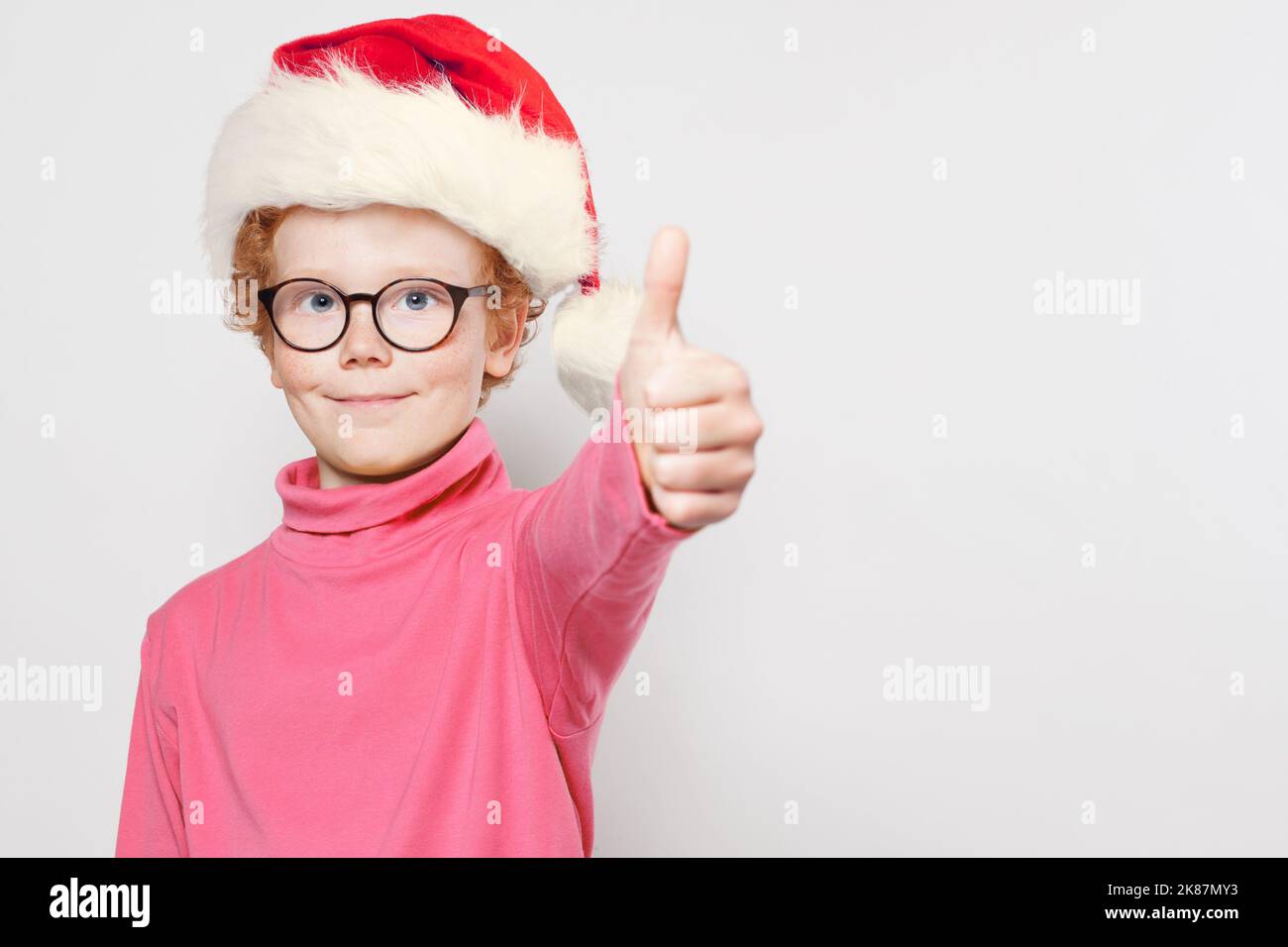 Little redhead boy in Santa hat with thumb up on white background Stock ...