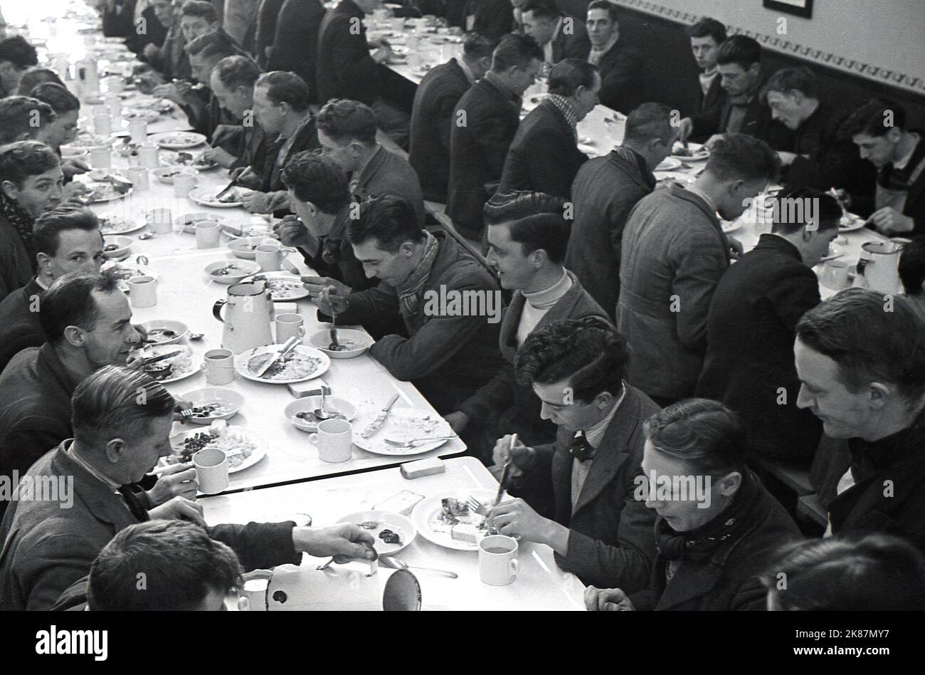 1937, historical, male workers sitting together at long tables eating a ...