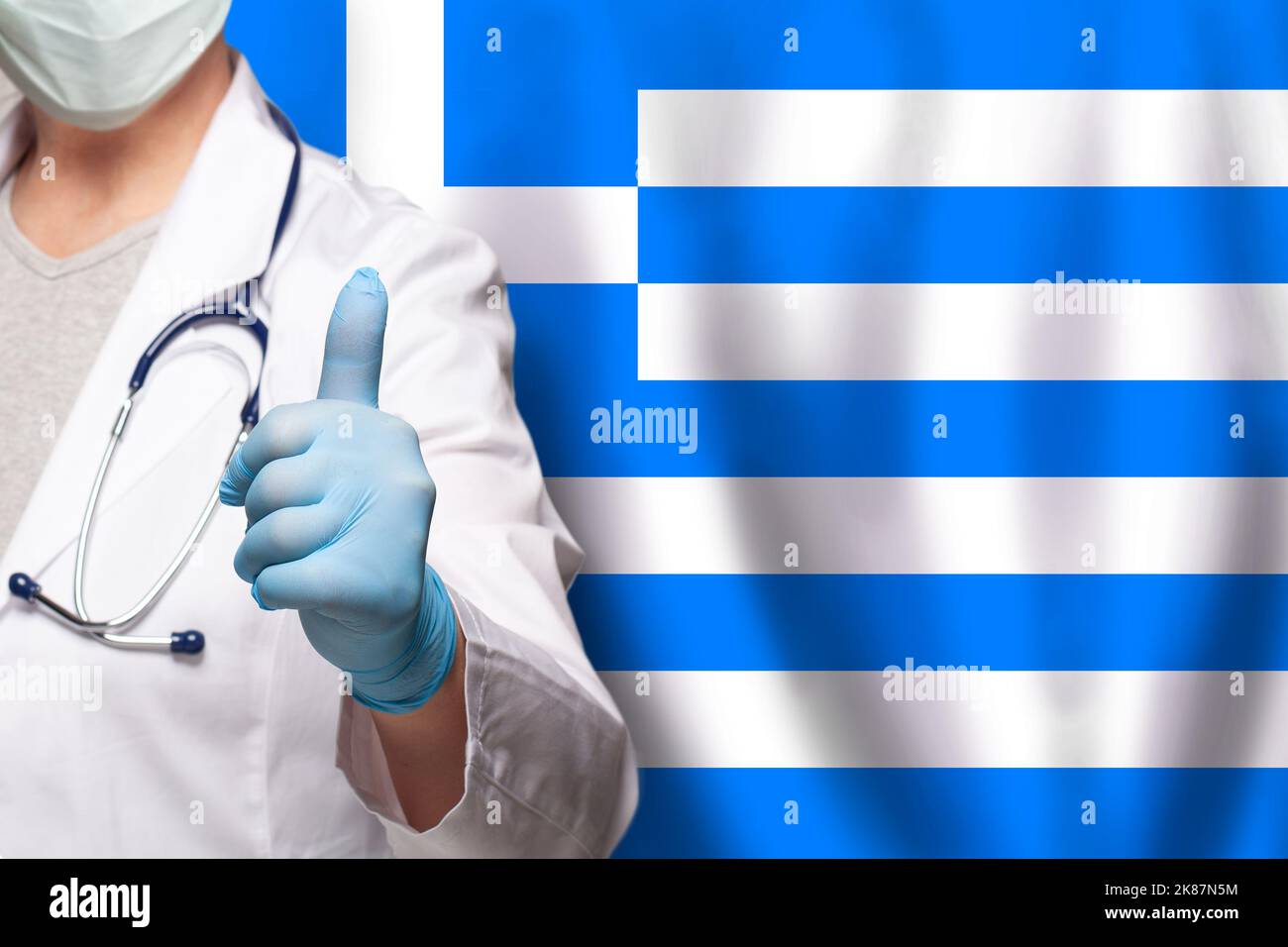 Greek doctor's hand showing thumb up positive gesture on flag of Greece ...