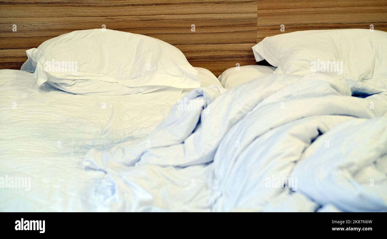 Bed with pillows and crumpled blanket. Crumpled blanket and pillows on ...