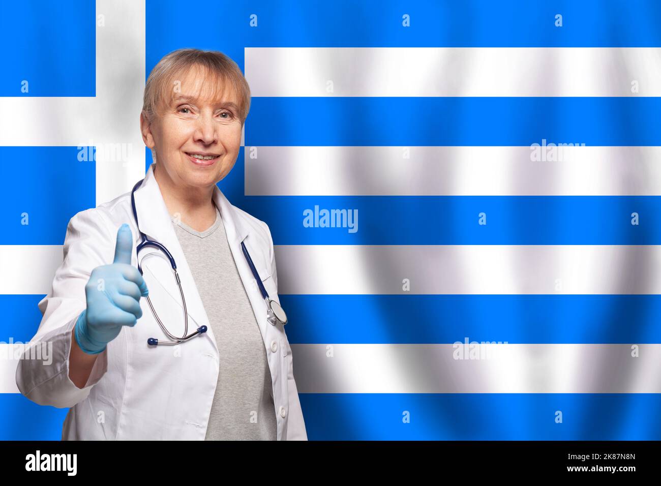 Greek smiling mature doctor woman holding stethoscope on flag of Greece ...