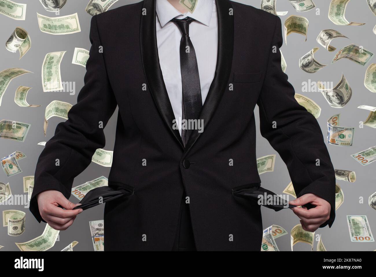 Poor person with empty pockets under money rain on grey background ...