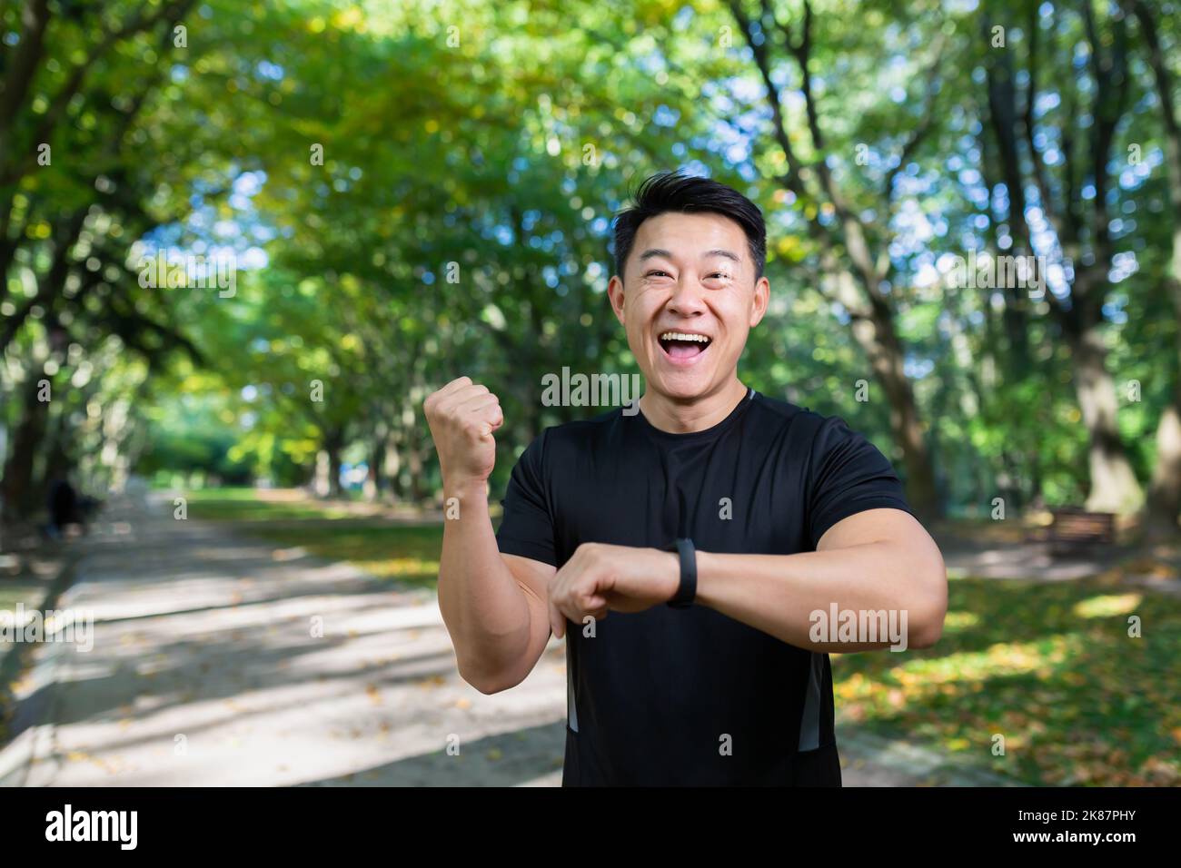 Male asian athlete on a morning run rejoices at the achieved result ...