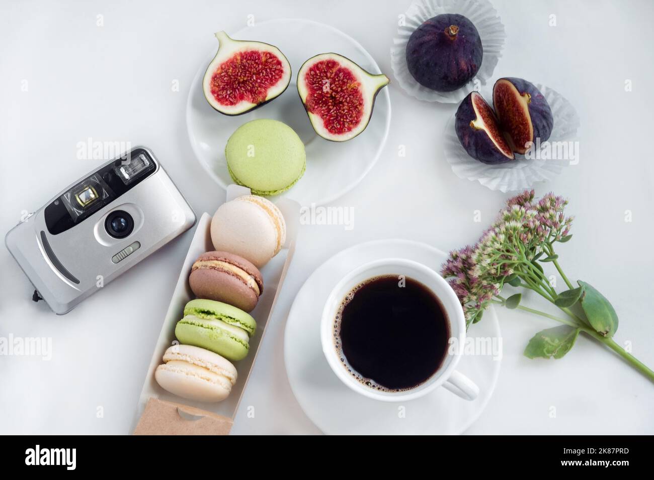 aesthetic film camera flatlay, cups of coffee, figs and macarons on a white background, top view ...