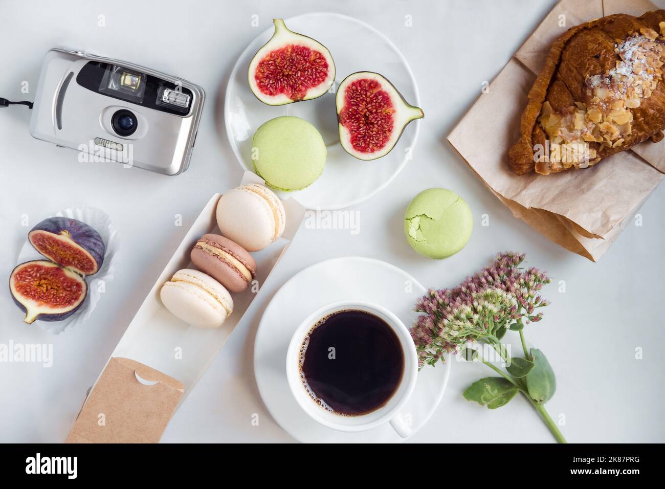 aesthetic film camera flatlay, cups of coffee, figs and macarons on a white background, top view ...