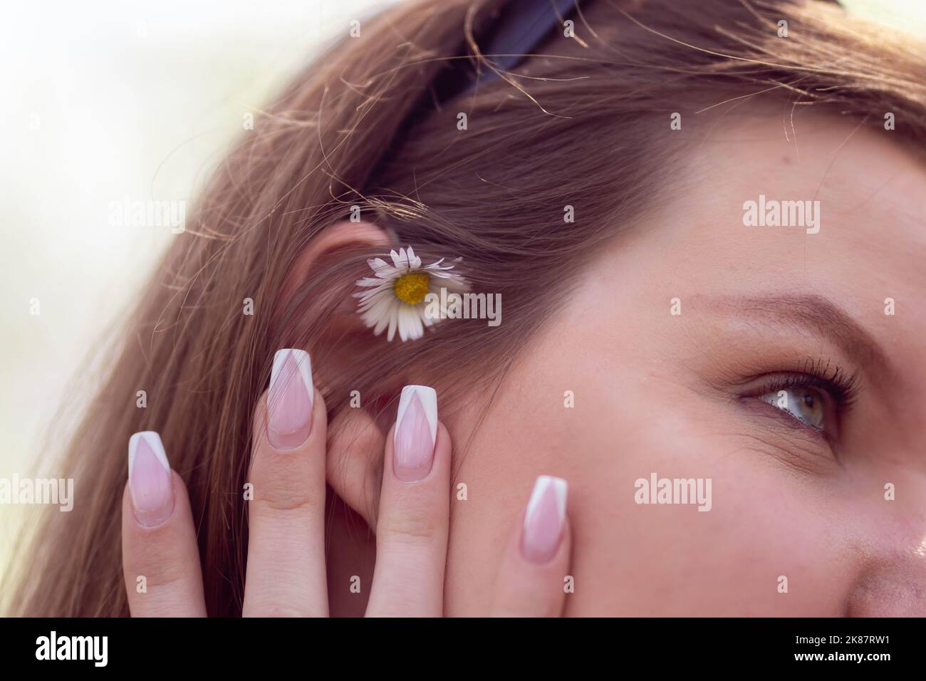 Portrait of a gorgeous young woman with a red flower behind her ear ...
