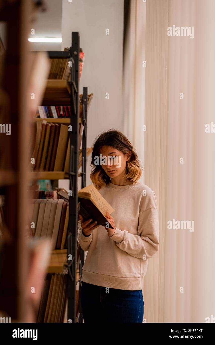 College girl turning sheets of a book in the library Stock Photo - Alamy