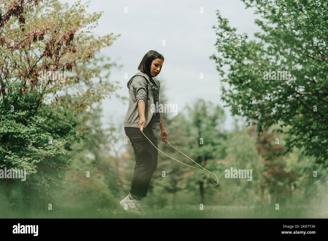 Beautiful girl jumping on the rope in the park Stock Photo - Alamy