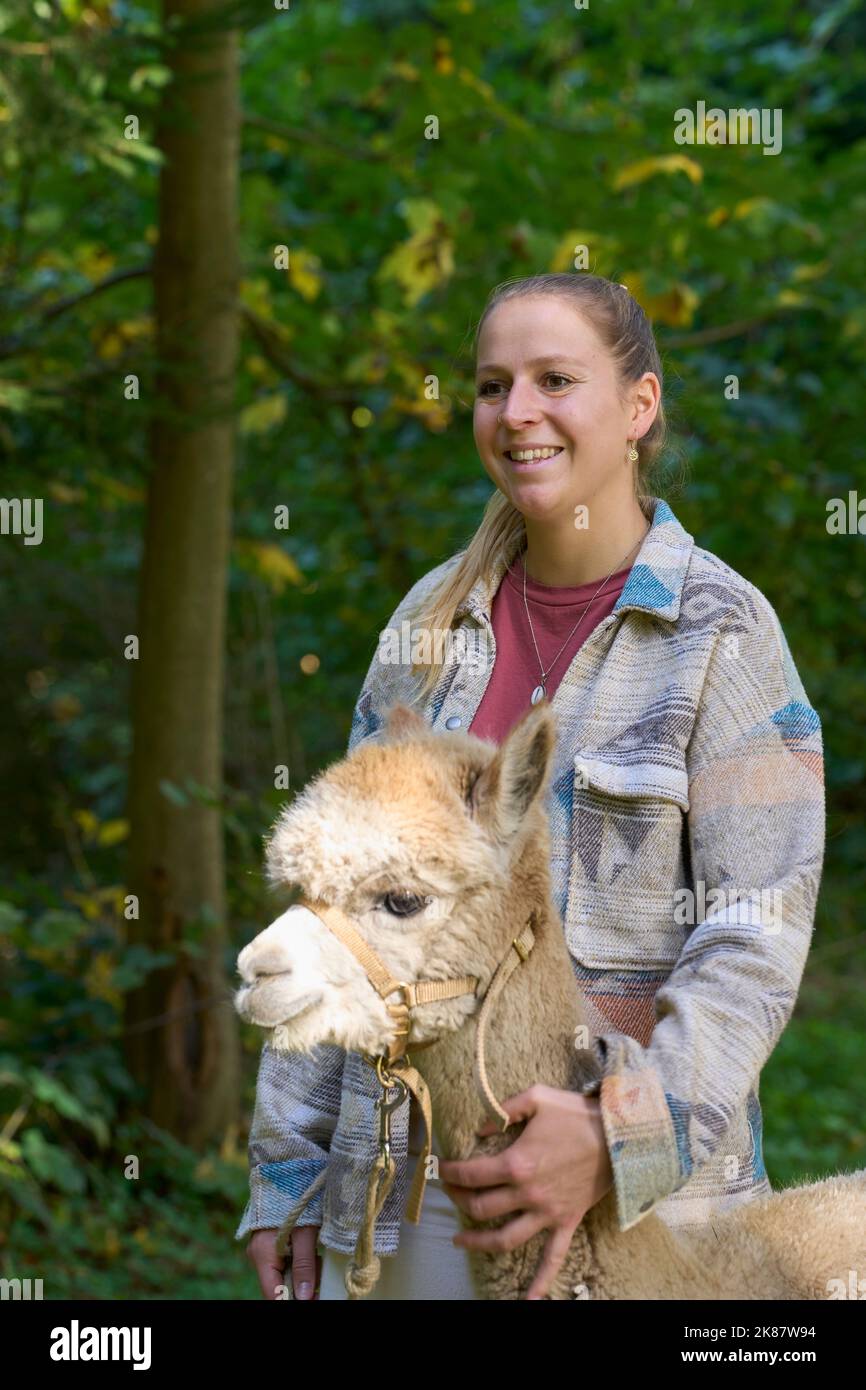A Sunbeam Meets Young Woman With Beige Alpaca On Forest Path. In The ...