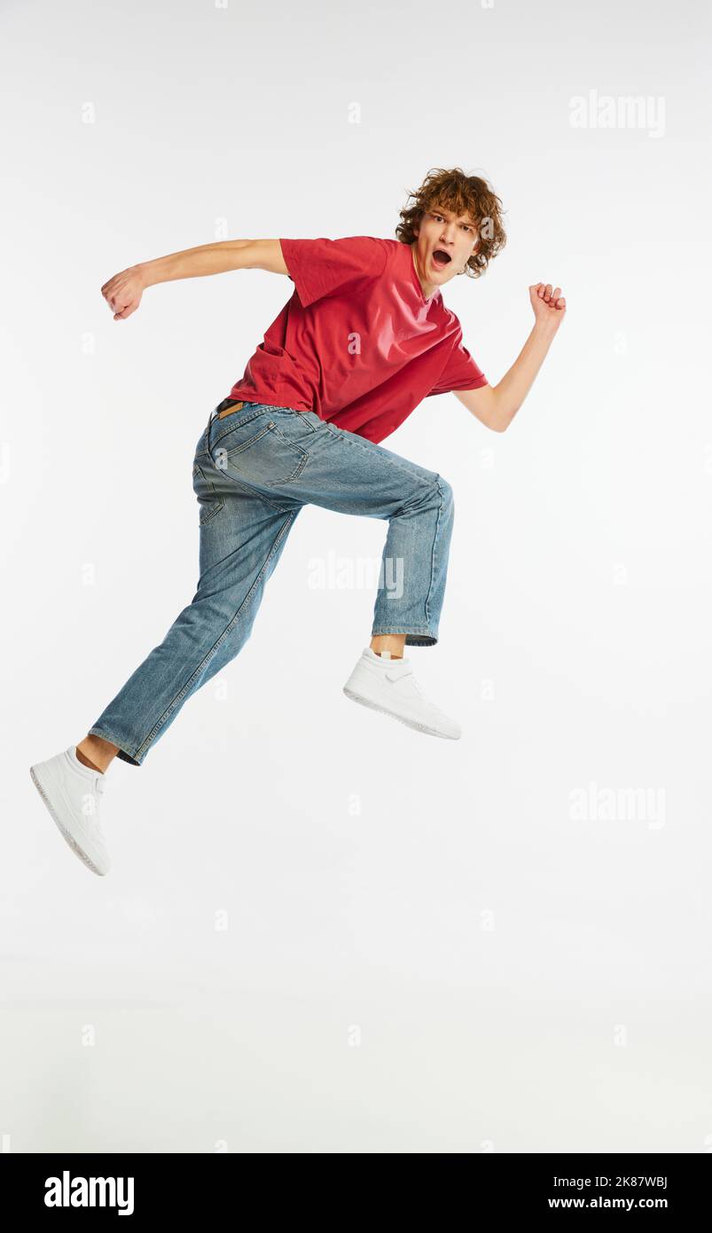 Full length portrait of excited young man running, dancing, having fun ...