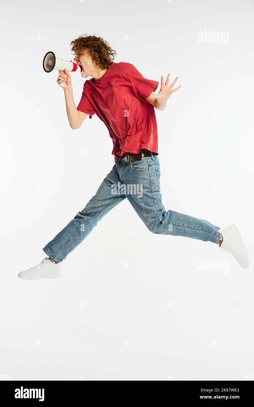 Full length portrait of excited young man jumping and shouting at ...