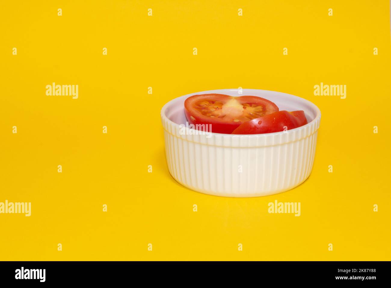 A closeup of cut tomato in a bowl isolated on yellow background Stock ...