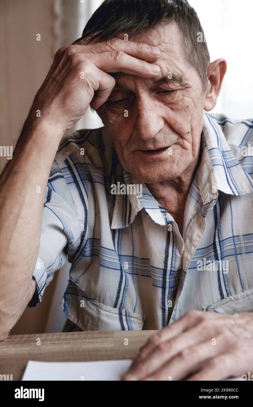 Senior sitting at the table and thinking about something or forg Stock ...