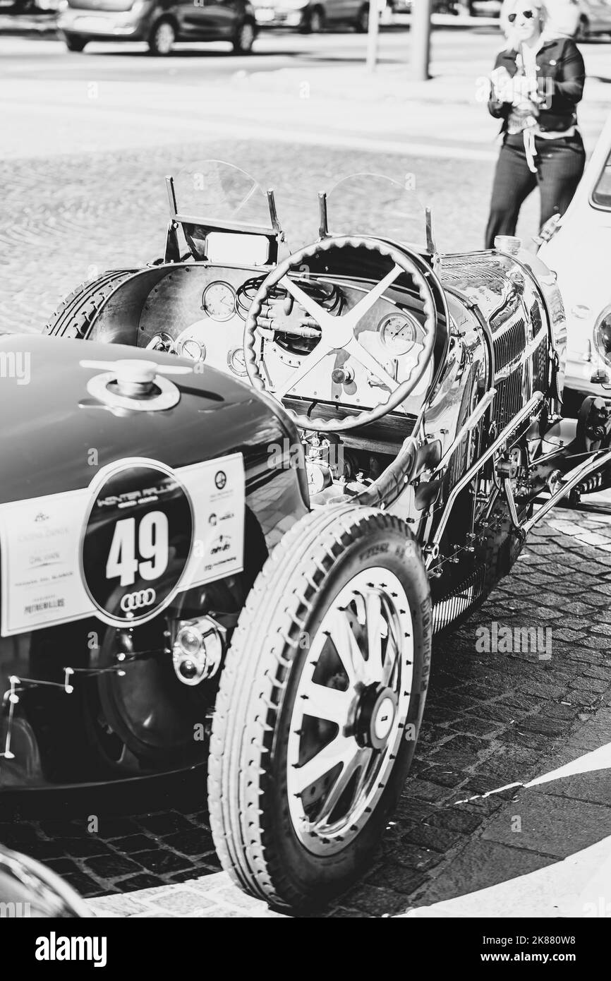 A vertical black and white shot of an old Bugatti car on the street in ...