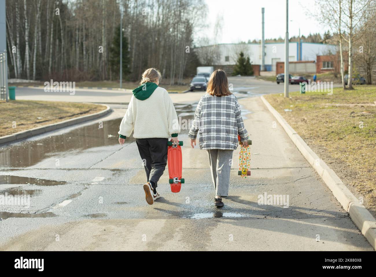 Girls walk with skateboards in their hands. Teenagers walk around city ...