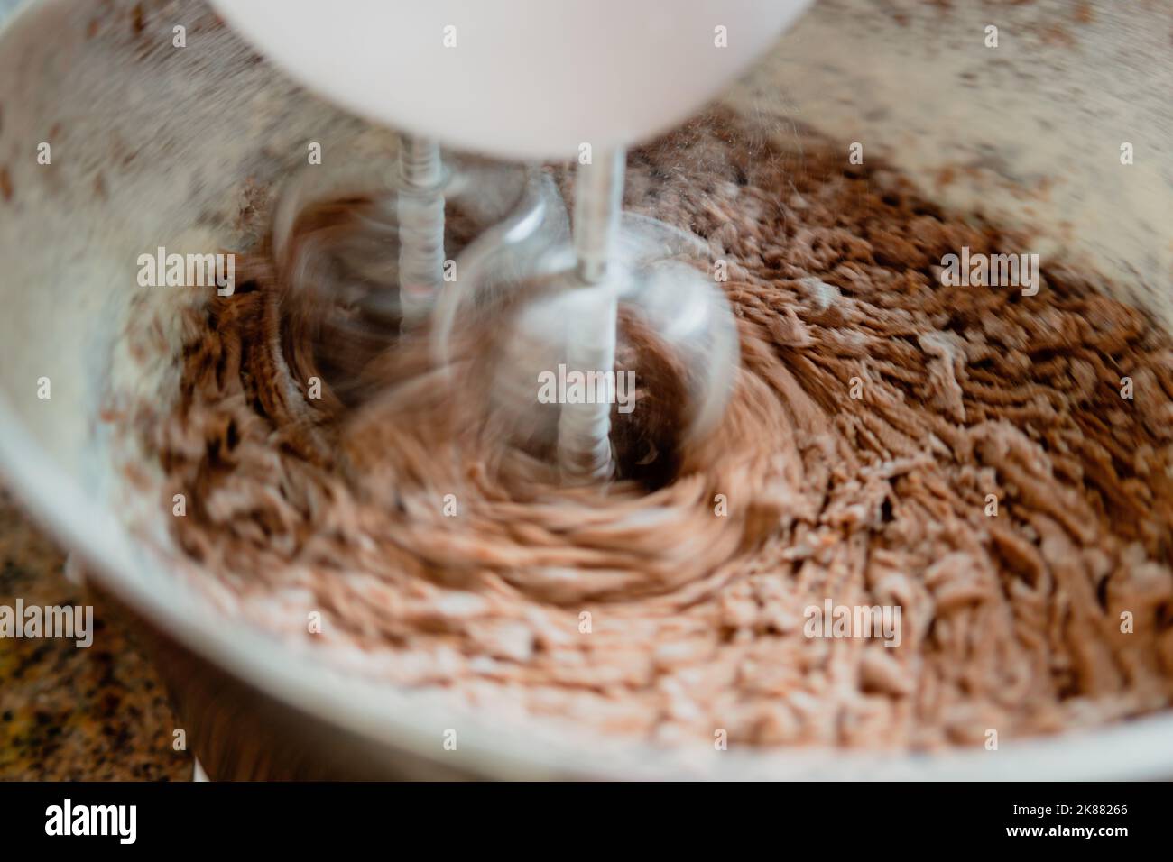 Close up of chocolate cake batter and flower in mixing bowl with ...