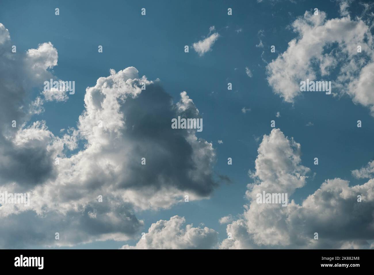 Puffy white clouds framed by intense blue sky and subtle sun rays Stock ...