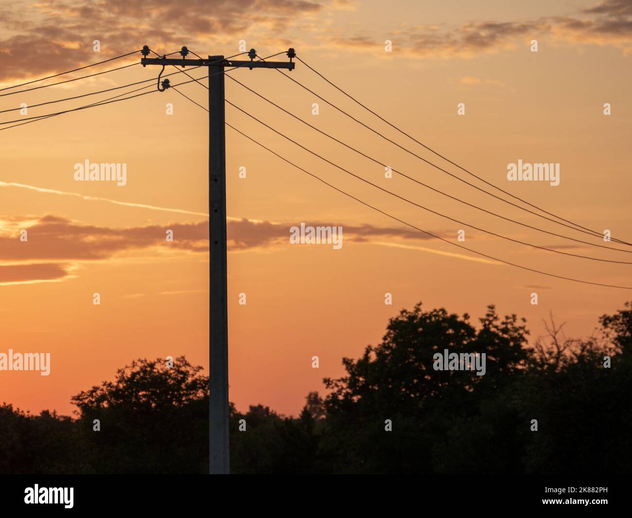 A silhouette of a power line with cables under a sunset sky Stock Photo ...