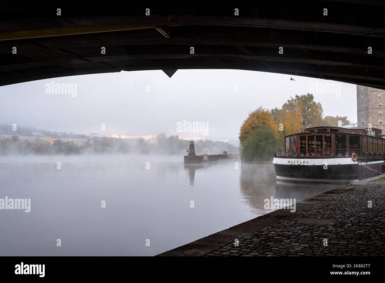 Autumn morning at Vltava riverside under Jiráskův bridge. Fog rises ...