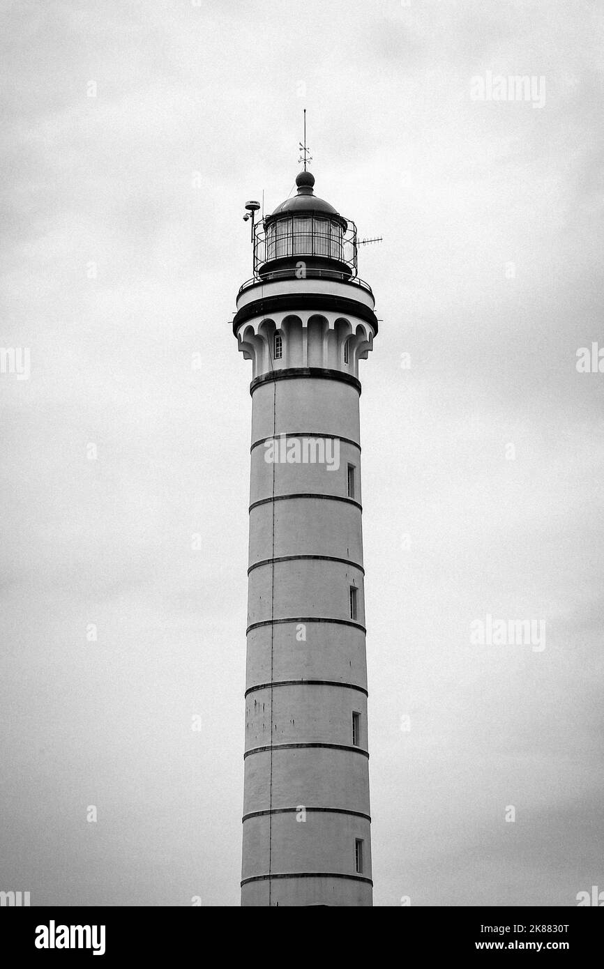 A vertical of a lighthouse against a cloudy sky shot in grayscale Stock ...