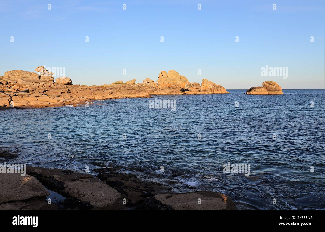 A scenic view of rocks on the beach against a sea on a sunny day Stock ...
