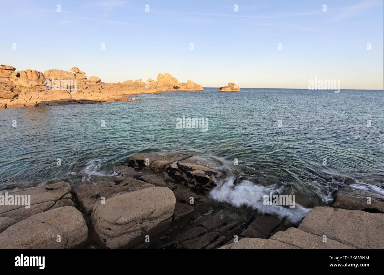 A scenic view of rocks on the beach against a sea on a sunny day Stock ...