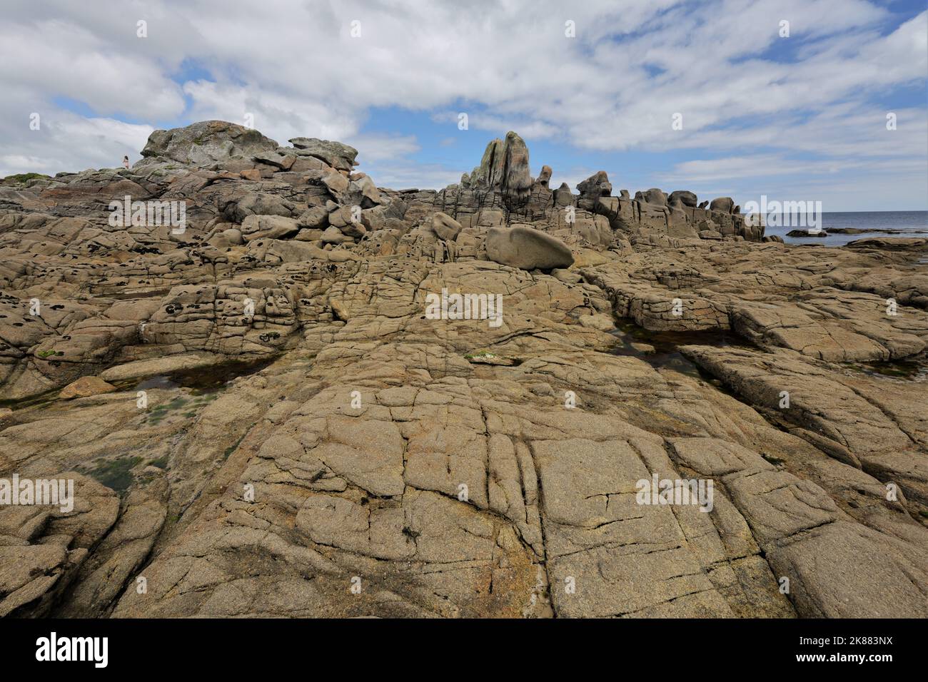 A scenic view of rocks on the beach against a sea on a sunny day Stock ...