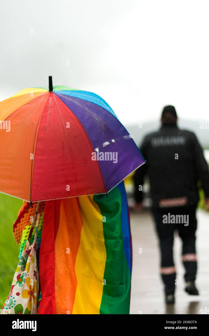 A vertical shot of a person with a pride flag and a rainbow umbrella at ...