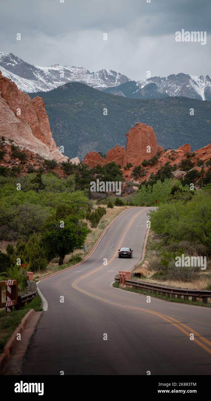 A vertical shot of a curved road with a single car leading to the red ...